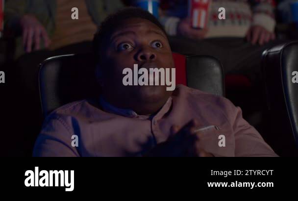 Close up of fat guy face watching action film in cinema. Young man ...