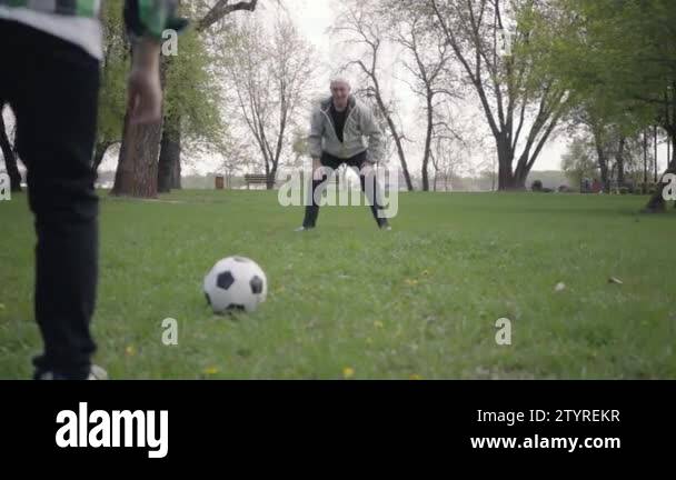 Grandson hitting the ball and grandfather missing the goal. Happy cute ...