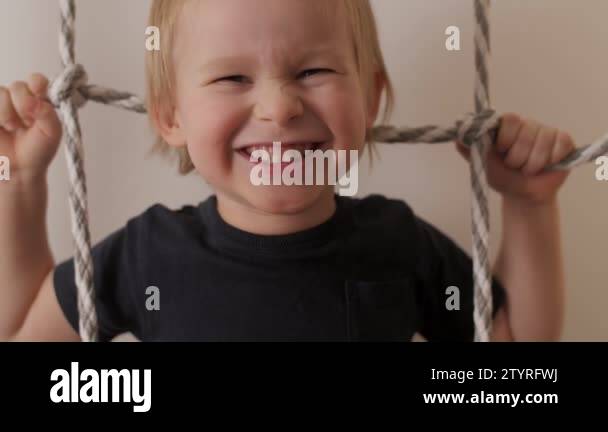 Close up face of laughing cute little boy posing on rope ladder having ...
