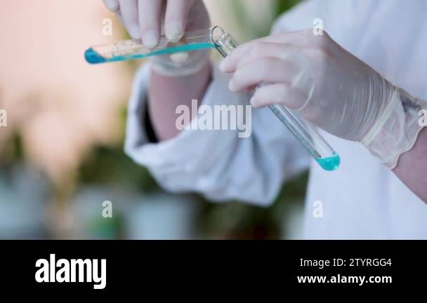 Scientist hand pouring a chemical solution from a laboratory glass test ...