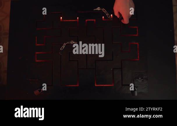 Top view of a black board with a carved labyrinth, a lock and several ...