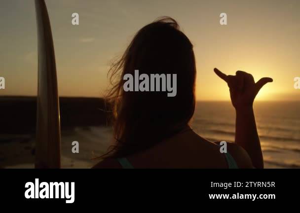 SLOW MOTION CLOSE UP: Unrecognizable girl with long flowing hair gazing at golden sunset giving ...