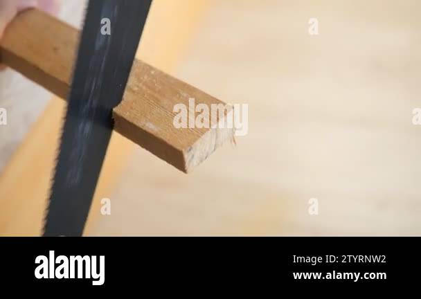 Man saw off the board with a hacksaw. Sawing a piece of wood with a ...