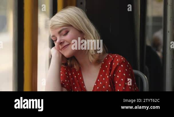 Portrait of young happy woman looking out a window, while she is ...