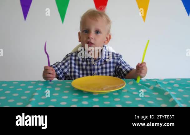 boy hit table with plastic knife and fork and waits for food. Gimbal ...