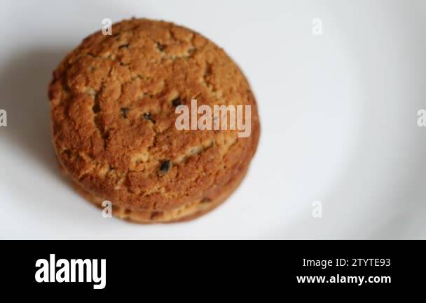 Oatmeal cookies are stacked on white plate. Male hand takes sweet ruddy ...