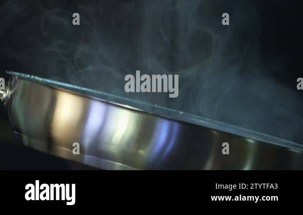 Splashes Oil, drops of water and smoke (vapor) come flying out of pan ...
