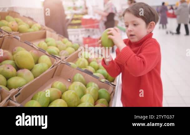 Funny little boy picking mango from the box, during family shopping in ...