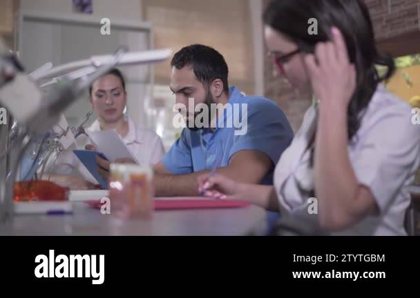 Multi-ethnic groupmates studying dentistry. Side view of Caucasian ...