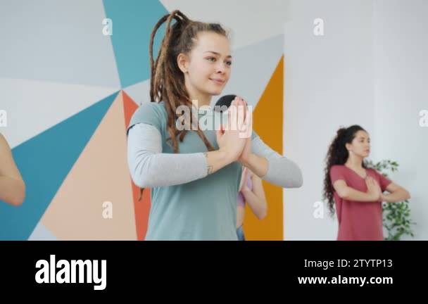 Cute girl doing yoga with group of people practising balance asanas ...