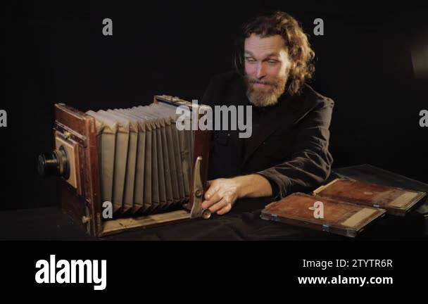 Bearded photographer in black clothes of 19th century, make photo with ...