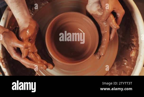 Hands of couple form a pot of clay on a potters wheel. A female hand ...