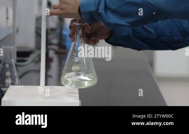 titration reaction by shaking colorless liquid in conical flask under a ...