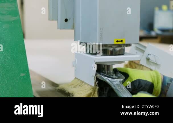 Operator of a modern CNC woodworking machine makes adjustments before ...