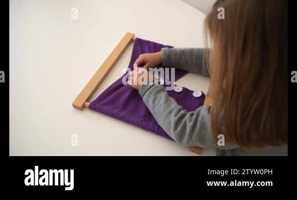 Little student girl of montessori pedagogy working with the buttoning ...