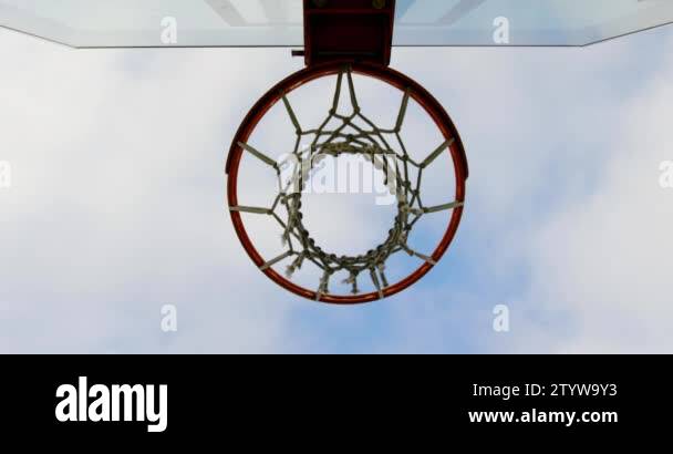 Upward view of basketball going through basketball hoop in basketball ...