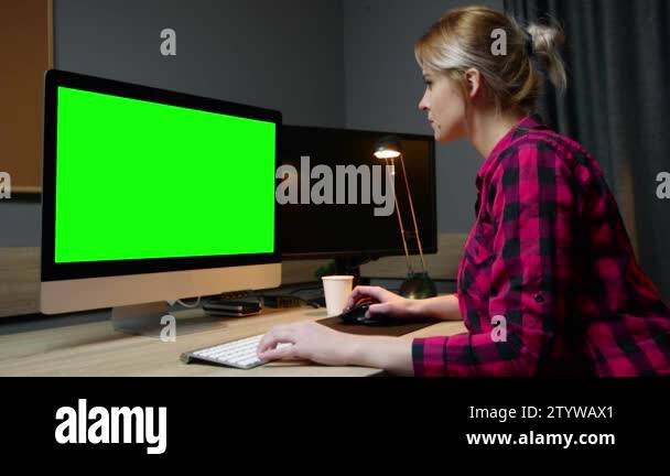Woman works on her computer, works in office. Monitor green screen ...