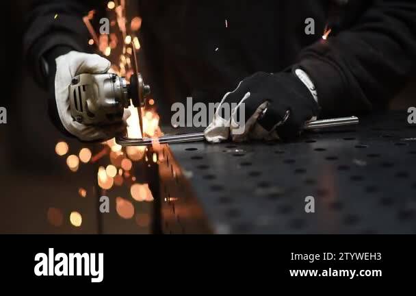 A welder, using an angle grinder, produces custom clamps for working on ...