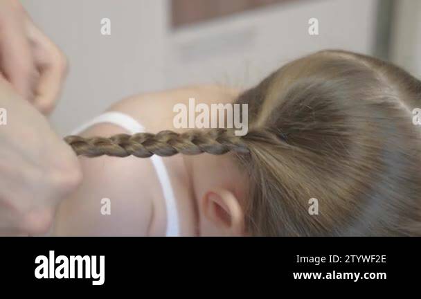 Mom Braids the Braid Of Her Little Daughter. mother combs the childs ...
