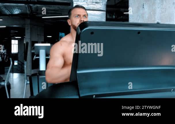 An attractive young man bodybuilder running on the treadmill with an ...