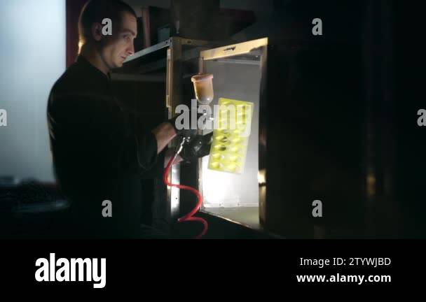 Man paints the detail in yellow color by spray gun in exhaust hood ...