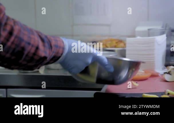 The cook lowers into a boiling oil fryer with French fries. Metal box ...