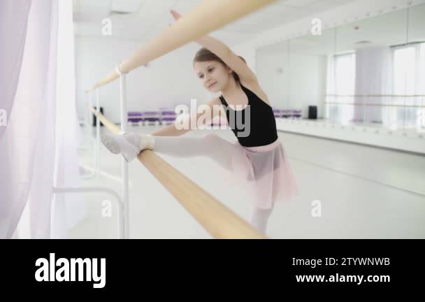Little girls using ballet barre when doing leg stretching exercises in ...