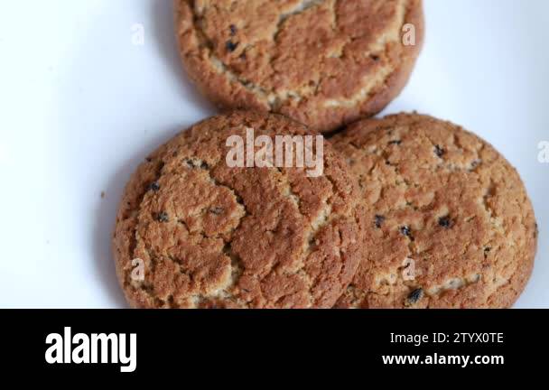Oatmeal cookies are lie on white plate. Male hand takes sweet ruddy ...