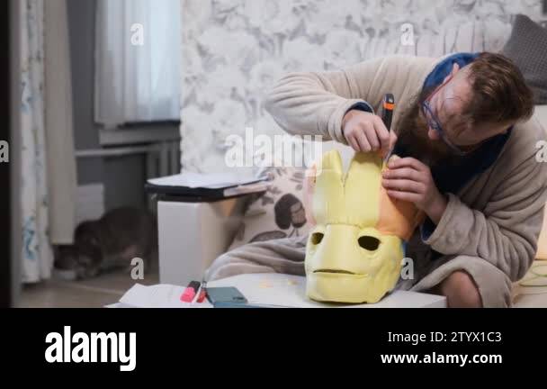 man in housecoat works at home making costumes for comic con with his ...