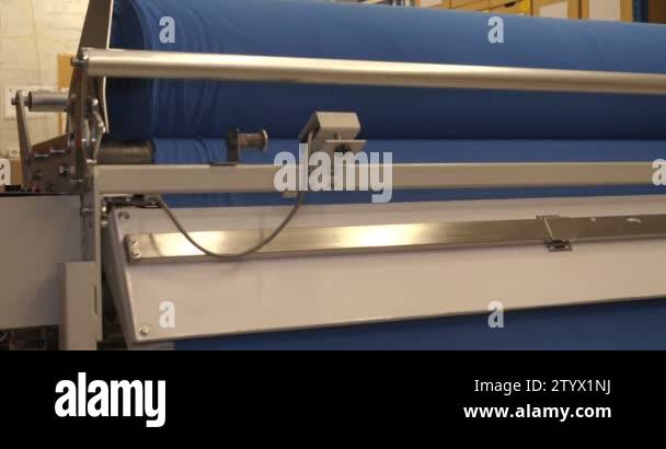 The garment factory takes a sample of a roll of blue fabric checking ...
