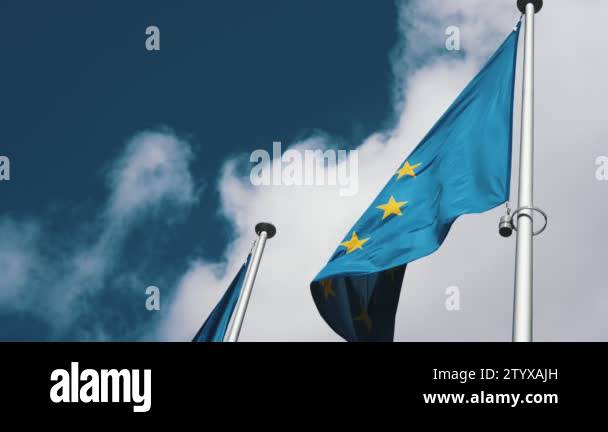 The EU flag fluttering proudly in a cloudy blue sky in spring in slow ...