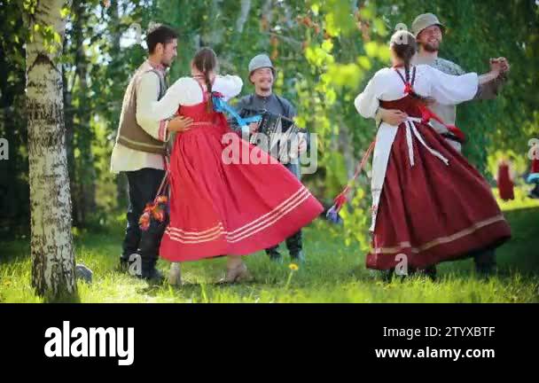 Two couples in Russian clothes dancing traditional dances on the field ...