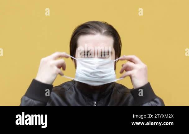 man puts on and removes a disposable mask to protect against the ...