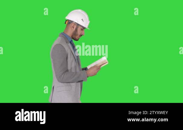 Young architect reading textbook or notebook while walking on a Green ...