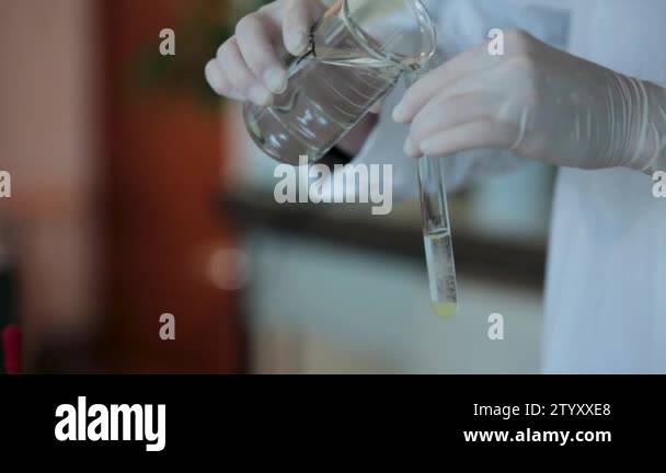 Scientist hand pouring a chemical solution from a laboratory glass test ...