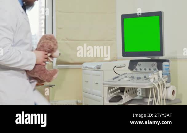 Pediatrician holding teddy bear, ultrasound scanner with green screen ...