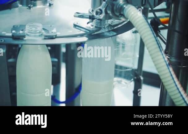 Plastic bottles filling with milk. Milk pouring into plastic bottle at ...