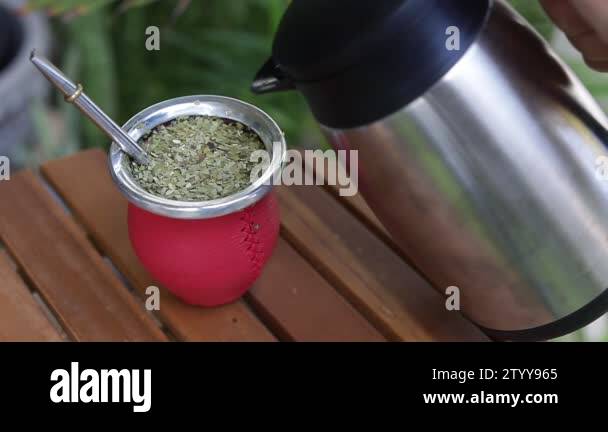 Man making yerba mate tea. Close up pouring hot water into traditional ...