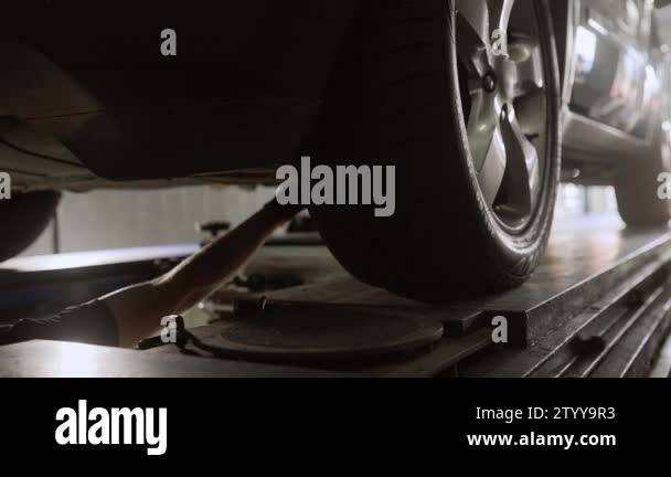 Mechanic moves and prepares car on the service stand for wheel ...