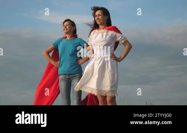 two girls in red cloaks of superheroes stand against a blue sky, the ...