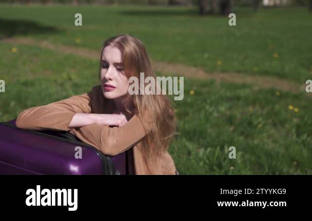 Sad traveler missed her flight and bus - Sitting on her luggage ...