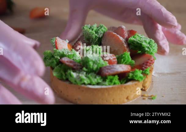 Pastry chef in rubber gloves shows the filling of cutting in half ...