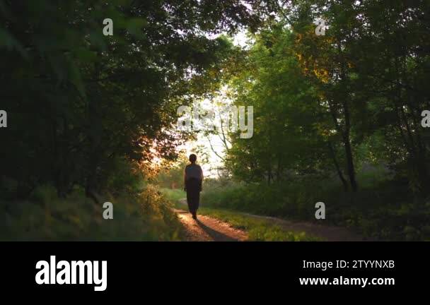 Redhead woman in pants and white shirt walking - Sunset country off road with beautiful evening ...