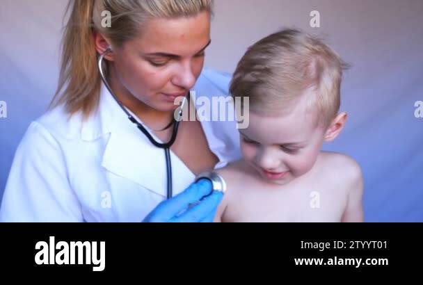 A young nurse listens to the lungs of a child using a stethoscope, then ...
