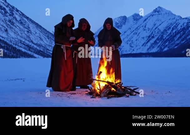 Group of monks in brown cloaks of the order of St. Francis are warming ...