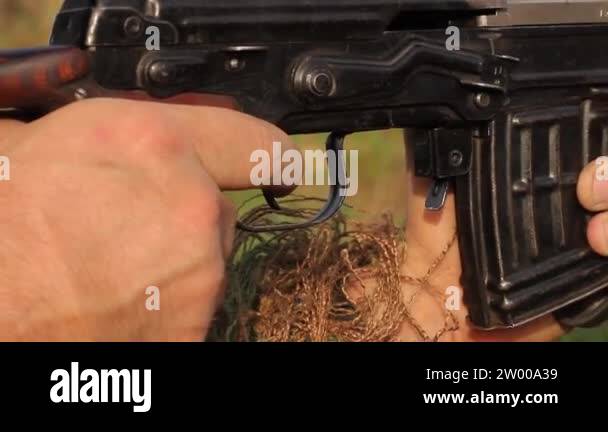 Close-up of a man's hand gripping the handle of a sniper rifle and ...