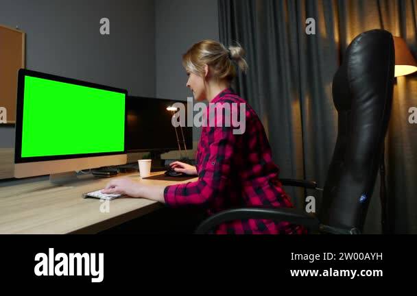 Woman works on her computer, works in office. Monitor green screen ...