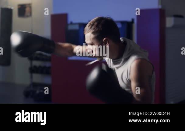 Brutal boxer in boxing gloves making strikes with shadow indoor, slow ...