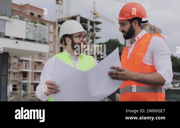 Architect expert engineers talking and analyze design plan standing under construction site ...