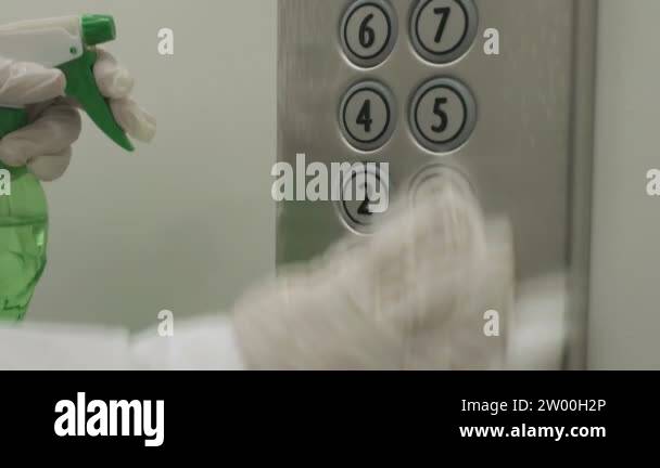 Woman using wet wipe and alcohol sanitizer spray to clean an elevator ...
